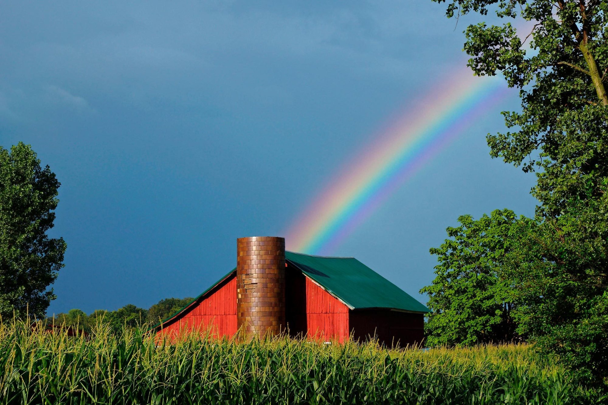 Solve Rainbow over barn jigsaw puzzle online with 77 pieces